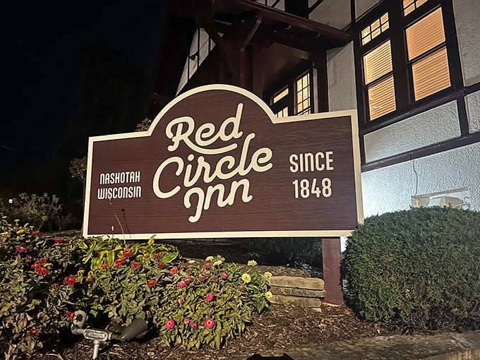 The iconic Red Circle Inn glows like a beacon against the twilight sky, promising warmth and culinary treasures within its Tudor-style walls.