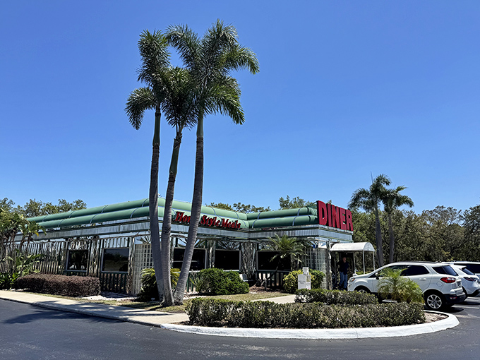 The classic green-trimmed exterior with bold red "DINER" signage stands like a beacon of comfort food against Florida's impossibly blue sky. Palm trees included, no extra charge.