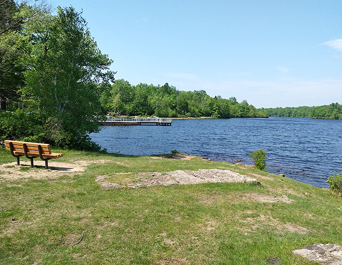 A wooden bench invites contemplation beside Tobyhanna Lake's shimmering waters. Nature's version of front-row seats to Pennsylvania's most peaceful show.