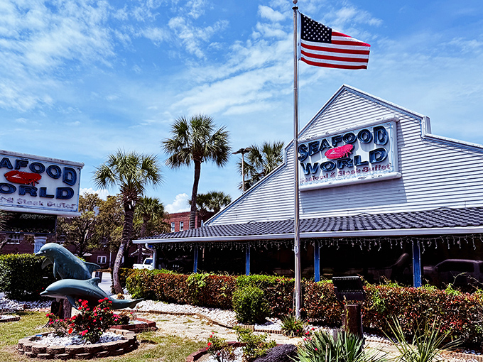 The classic coastal charm of Seafood World beckons under Carolina blue skies, where that American flag promises patriotic portions of seafood treasures.