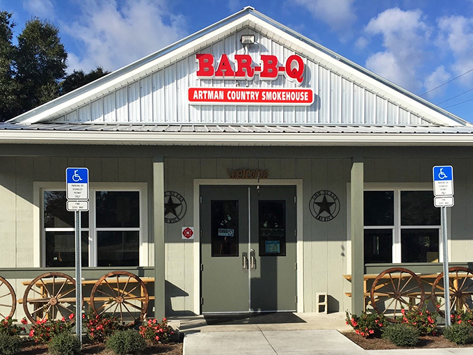 The white clapboard exterior of Artman Country Smokehouse beckons like a barbecue beacon, complete with rustic wagon wheels that say "slow down, good food ahead."