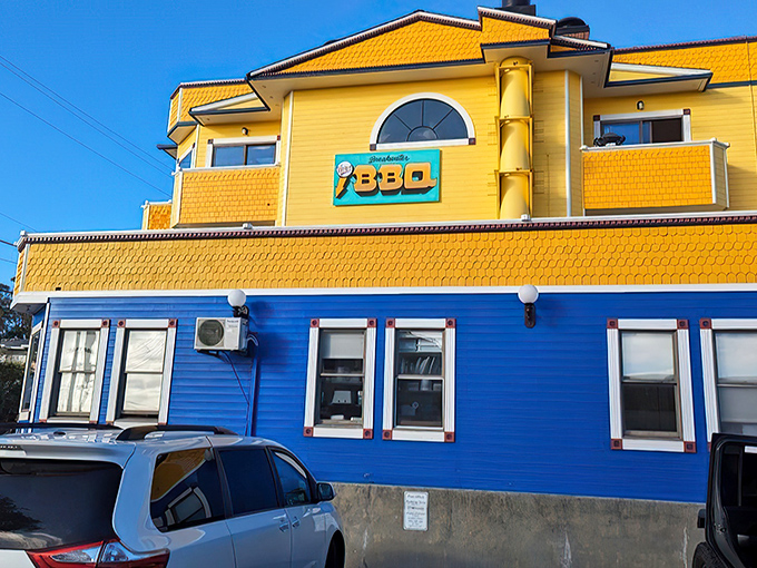 The sunshine-yellow and ocean-blue building stands like a beacon of barbecue hope on the coastline, promising smoky treasures within.