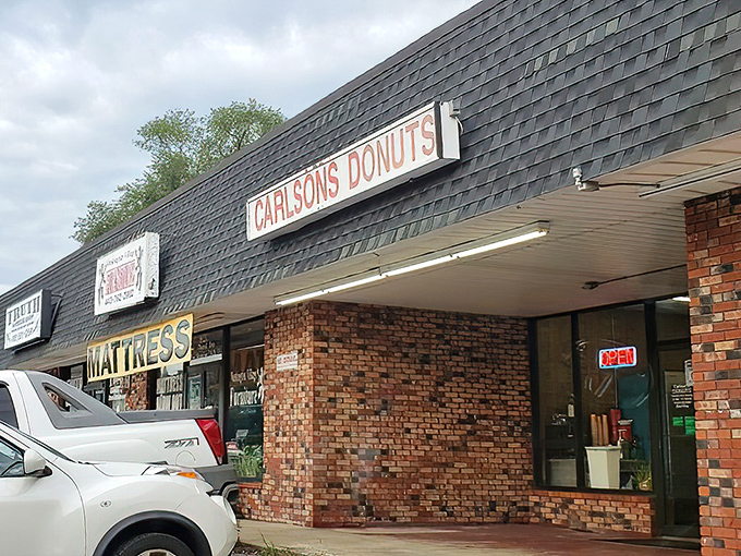 The unassuming brick facade of Carlson's Donuts stands like a beacon of sweetness among the strip mall surroundings. No frills, just donut thrills.