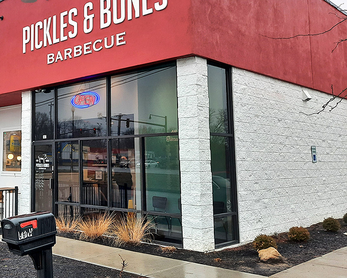 The bright red exterior of Pickles & Bones stands like a barbecue beacon in Milford, promising smoky treasures within.