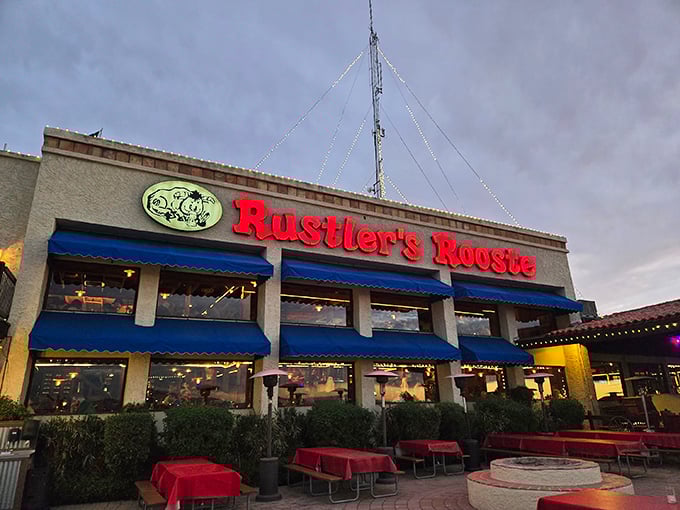 Rustler's Rooste stands proud against the Arizona sky, its blue awnings and glowing sign beckoning hungry travelers like a carnivorous oasis in the desert.