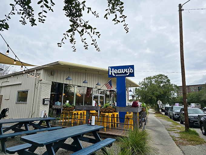 Heavy's blue sign glows like a beacon for burger pilgrims. The charming patio with those signature yellow stools practically whispers, "Sit here, happiness awaits." 