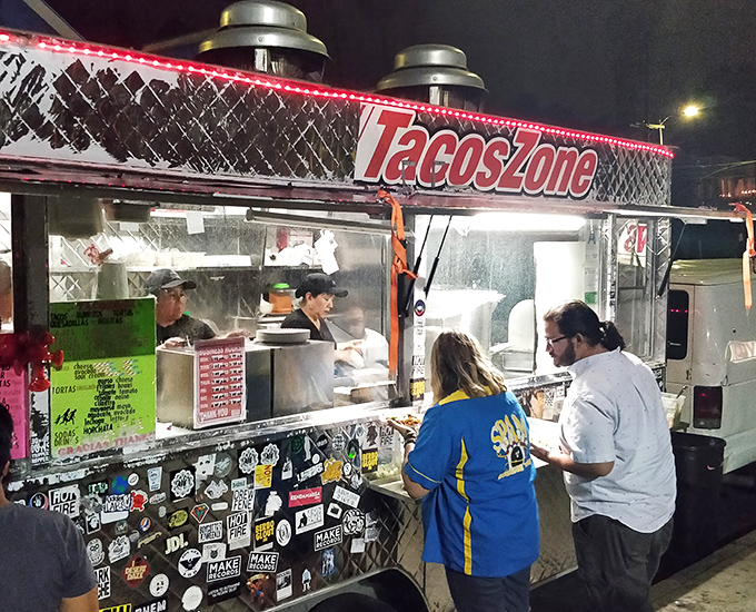 The silver chariot of late-night salvation, Taco Zone's sticker-adorned truck gleams under streetlights like a beacon to hungry night owls across Echo Park.