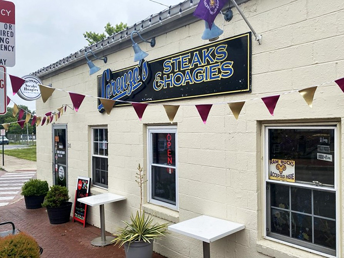 The unassuming white building with festive pennants might not look like food paradise, but locals know better. Sandwich nirvana awaits behind that blue neon sign.
