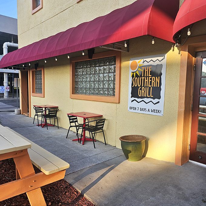 The welcoming exterior of The Southern Grill, with its signature red awning and outdoor seating, promises comfort food treasures within. Open seven days a week for your barbecue emergencies.