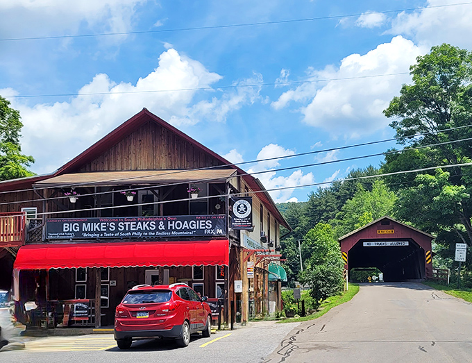 Rustic wooden charm meets sandwich paradise. Big Mike's stands proudly in Forksville with that iconic red awning, while a covered bridge peeks shyly from the right.