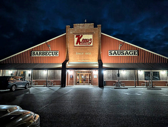 The iconic Kreuz Market stands like a barbecue cathedral against the Texas night sky, its red sign a beacon calling hungry pilgrims home.