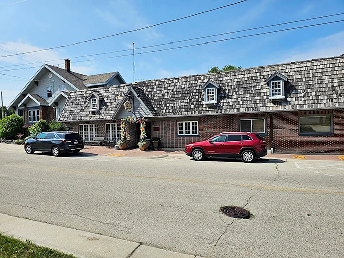 The distinctive shingled roof and brick exterior of Schwarz's Supper Club stands as a beacon of culinary tradition along a quiet New Holstein street.