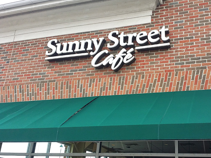 The unassuming brick exterior of Sunny Street Caf&eacute;, where culinary magic happens behind those modest green awnings. Breakfast nirvana awaits!