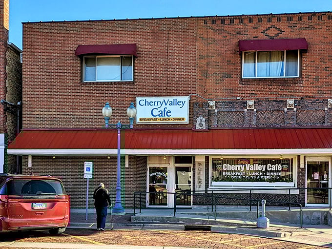 The brick facade and burgundy awning of Cherry Valley Cafe stands as a beacon of breakfast hope on Main Street, promising comfort food and conversation inside.