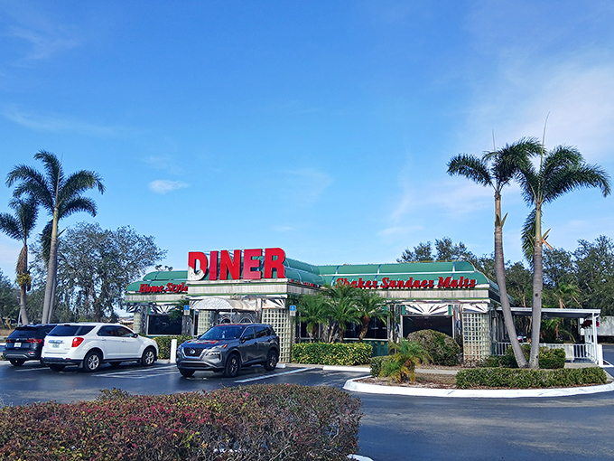 The classic green-trimmed exterior with bold red "DINER" signage stands like a beacon of comfort food against Florida's impossibly blue sky. Palm trees included, no extra charge. 