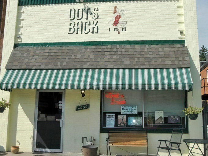 The unassuming white brick facade of Dot's Back Inn, with its vintage green striped awning, promises comfort food magic within these humble walls.