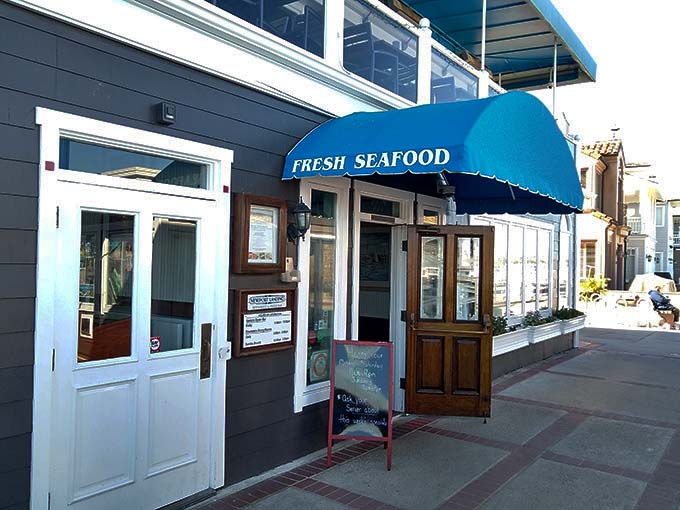 Newport Landing's blue-trimmed exterior stands like a maritime sentinel on the harbor, promising seafood treasures within those nautical-themed walls.