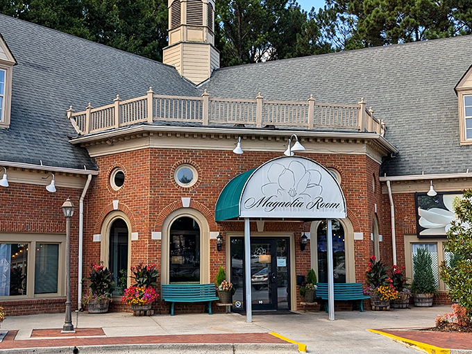 The brick exterior of Magnolia Room Cafeteria welcomes diners with Southern charm, complete with teal benches and colorful flower arrangements that practically whisper "come on in, y'all."