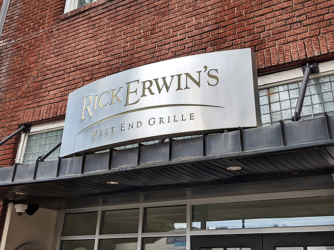 The elegant silver signage against classic brick announces Rick Erwin's West End Grille like a beacon for hungry Greenville locals seeking culinary salvation.