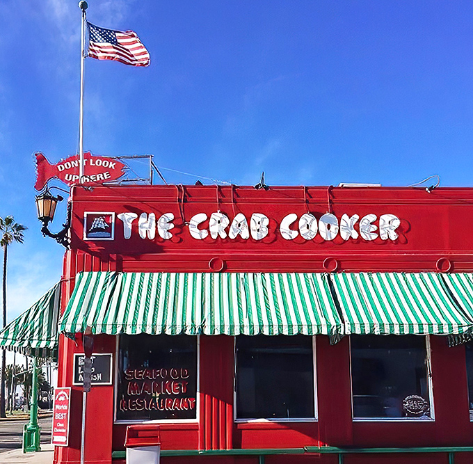 The fire-engine red exterior of The Crab Cooker stands out like a culinary lighthouse, complete with that iconic fish sign practically shouting "seafood paradise ahead!"