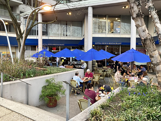 Little Pete's outdoor seating area beckons with cheerful blue umbrellas and bistro chairs. A perfect urban oasis for people-watching while savoring your morning coffee.