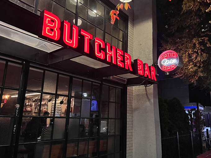 The neon-red Butcher Bar sign glows like a carnivorous lighthouse, beckoning hungry travelers through Philadelphia's evening darkness.