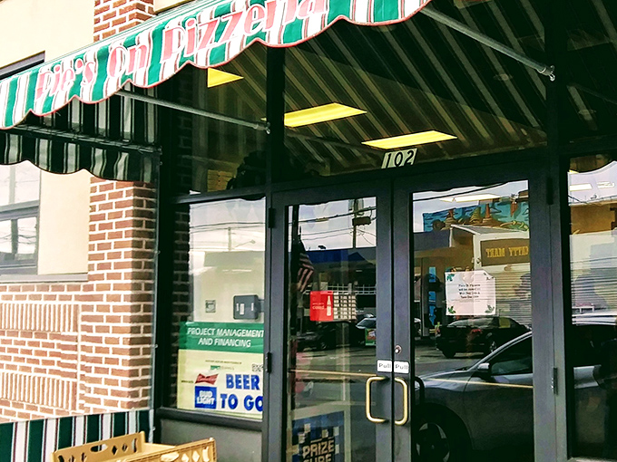 The green and white awning beckons like an old friend saying, "Hey, come get some pizza already!" Classic small-town charm with big pizza energy.