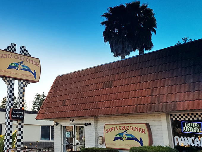 The iconic checkerboard sign welcomes hungry travelers like a coastal lighthouse for the famished. Classic California diner architecture with a surfer's twist.