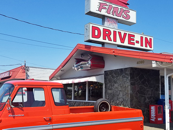 That iconic red sign beckons like a lighthouse for the hungry soul. Fins Drive-In stands proud against the Oregon sky, promising nostalgic delights within.