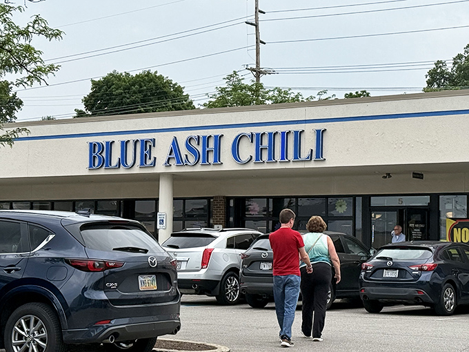 The blue lettering of Blue Ash Chili stands out against the strip mall backdrop like a neon promise of comfort food nirvana ahead.