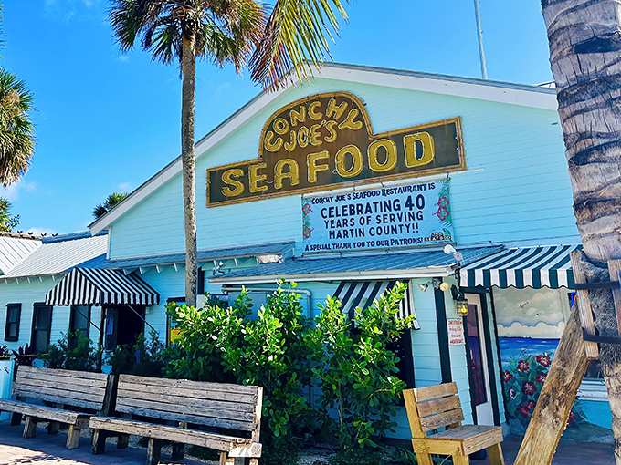 The pale blue exterior of Conchy Joe's stands like a tropical mirage against Florida's sky, promising seafood treasures within those weathered walls.