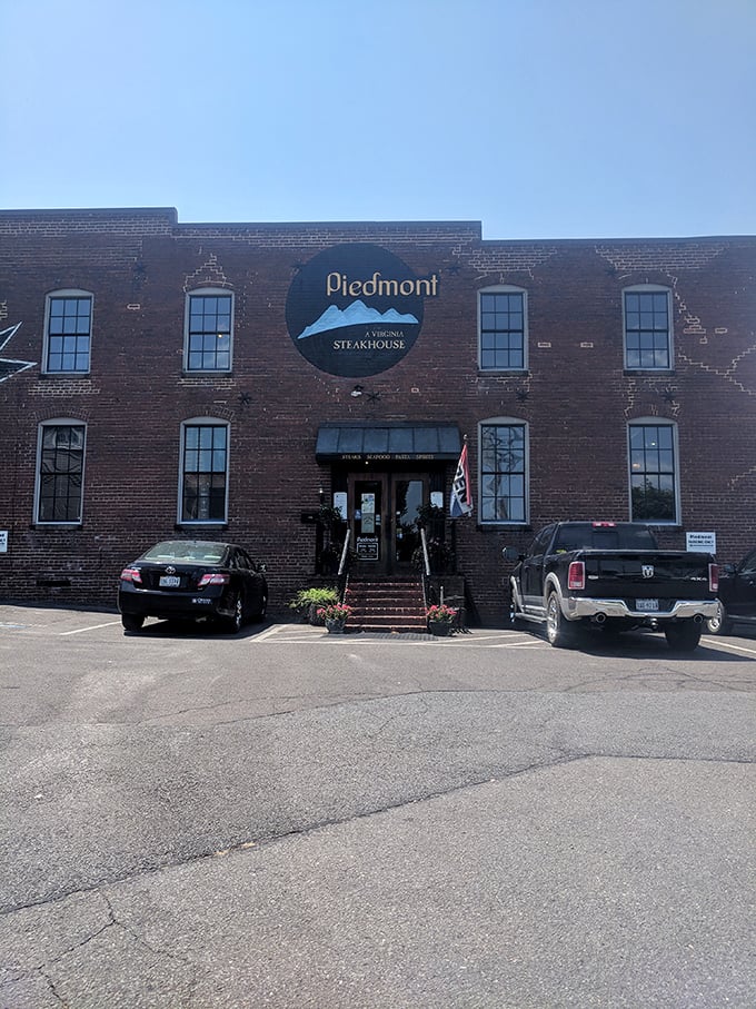 The historic brick exterior of Piedmont Steakhouse stands like a culinary fortress in downtown Culpeper, promising treasures within that the modest fa&ccedil;ade only hints at.