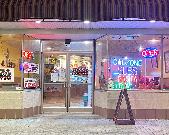 The blue and white striped awning of La Vera Pizzeria stands as a beacon of hope for the pizza-deprived. No frills, just neon promises of deliciousness within.