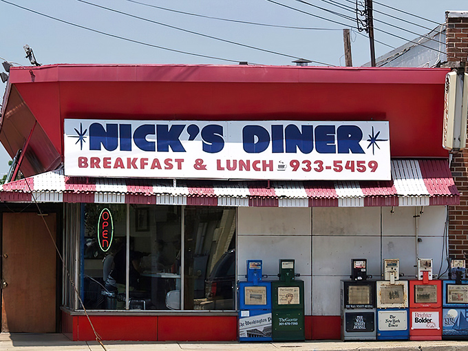 The classic red awning and bold blue lettering of Nick's Diner isn't just signage&mdash;it's a promise of unpretentious breakfast perfection waiting just beyond those newspaper boxes.