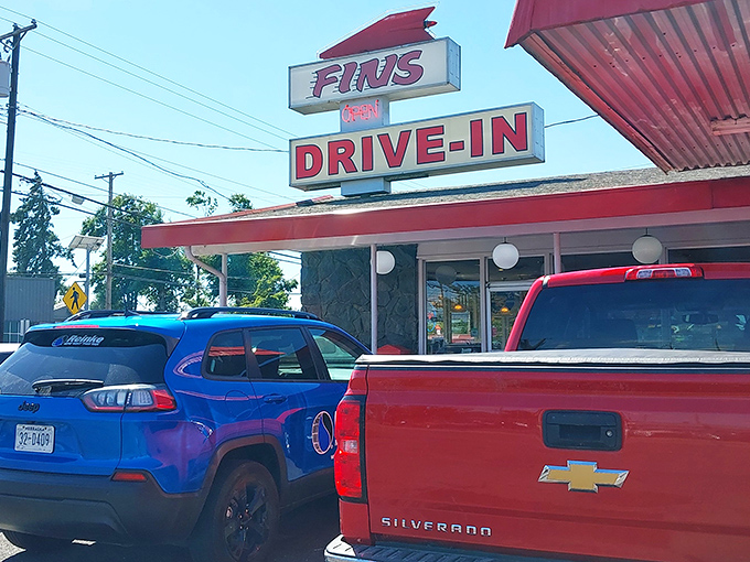 That iconic red sign beckons like a lighthouse for the hungry soul. Fins Drive-In stands proud against the Oregon sky, promising nostalgic delights within.