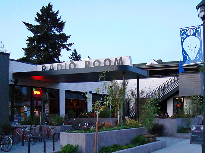 Radio Room's exterior perfectly preserves its 1949 gas station bones while promising something far more delicious than unleaded. The illuminated sign becomes Portland's culinary lighthouse after dark.