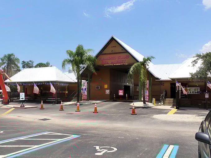 The iconic entrance to Flamingo Island Flea Market beckons with the promise of treasures waiting inside, palm trees standing guard like patient sentinels.