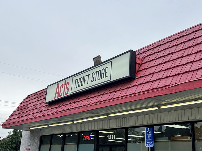 The iconic red roof of ACTS Thrift Store beckons bargain hunters like a lighthouse guiding ships to treasure-filled shores.