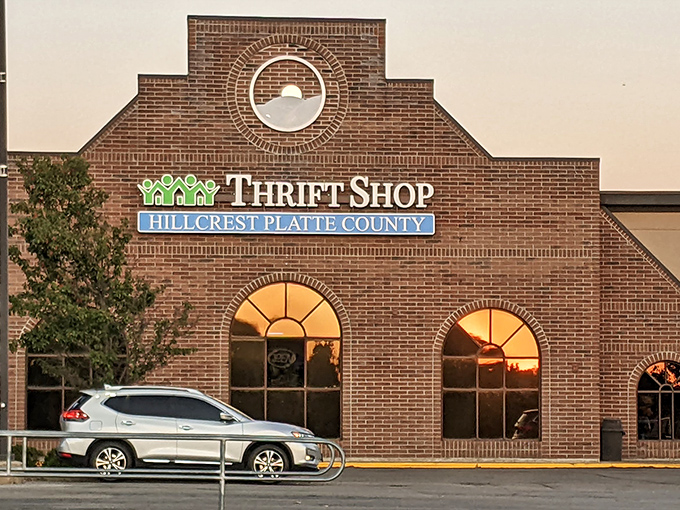 The stately brick facade of Hillcrest Thrift Shop beckons bargain hunters with its distinctive arched windows and warm, inviting glow at sunset.
