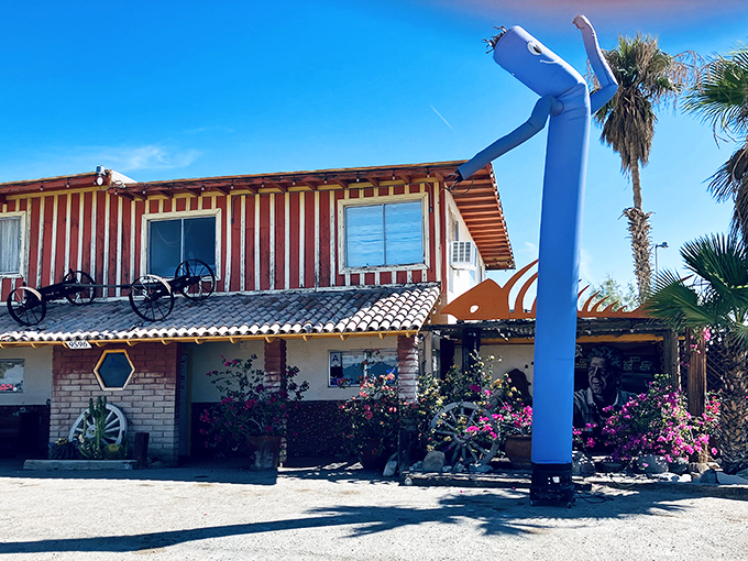 The Ski Inn's distinctive exterior stands like a mirage in the desert, complete with that quirky blue inflatable figure welcoming hungry travelers.