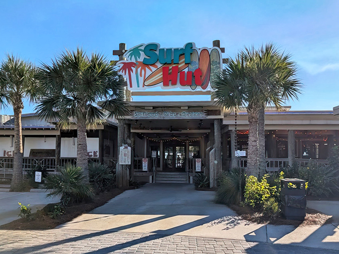 The iconic Surf Hut sign welcomes beach-goers with a promise of seafood paradise. Palm trees stand guard like culinary sentinels.