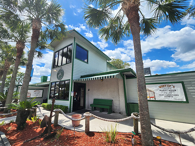 The unassuming exterior of Whitey's Fish Camp stands like a beacon for hungry travelers, palm trees swaying in welcome. 