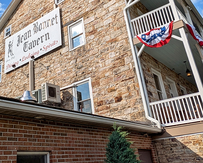 The historic limestone facade of Jean Bonnet Tavern stands proudly in Bedford, where patriotic bunting adds a touch of Americana to this centuries-old landmark.