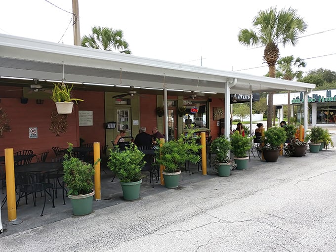 The salmon-colored exterior of Christo's Cafe welcomes you like a warm Florida morning, complete with lush greenery and shaded outdoor seating for those perfect Orlando days.