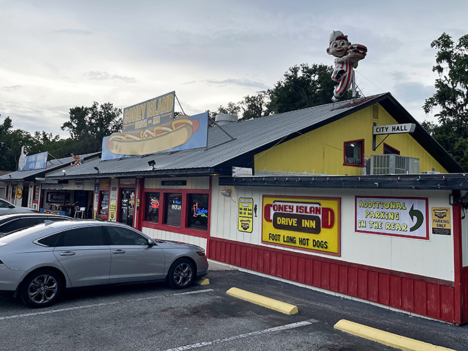 The bright yellow exterior of Coney Island Drive Inn stands out like a beacon of comfort food, complete with that iconic hot dog mascot keeping watch.