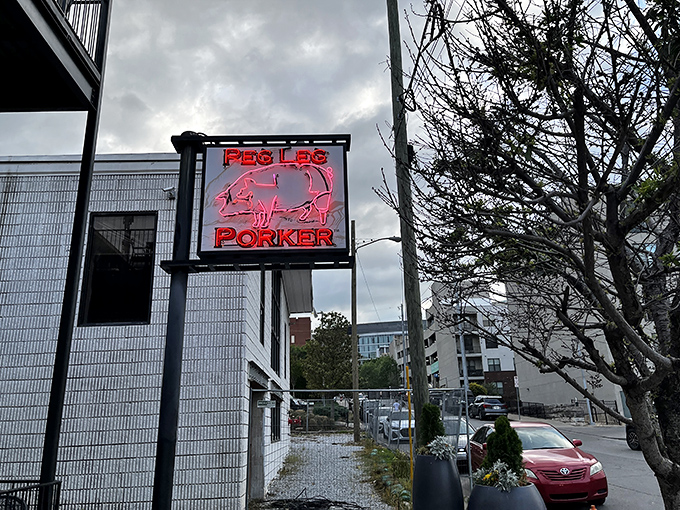 The neon pig sign glows like a beacon of barbecue hope in Nashville's Gulch neighborhood, promising smoky delights within these unassuming walls.