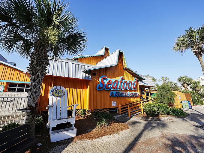 The bright orange exterior of Back Porch Seafood & Oyster House stands out like a cheerful beacon against Destin's blue sky, promising seafood treasures within.