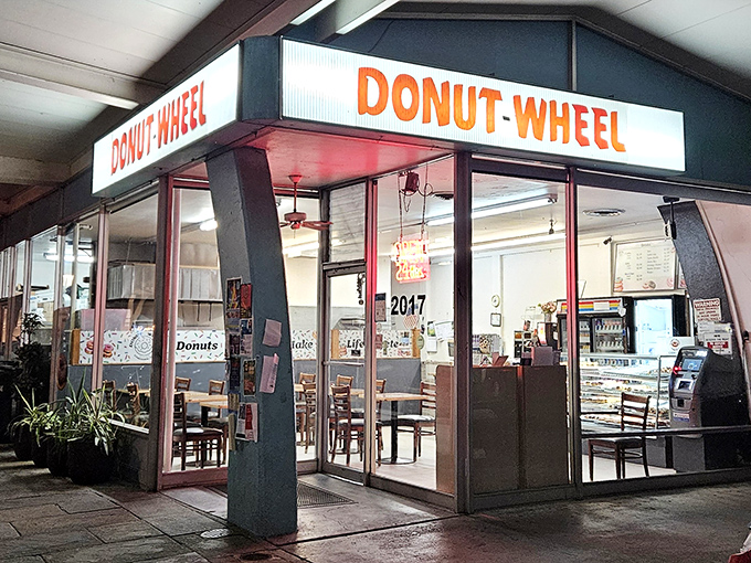 The glowing Donut Wheel sign beckons like a sugary lighthouse in the night. Simple, unpretentious, and promising sweet perfection inside.
