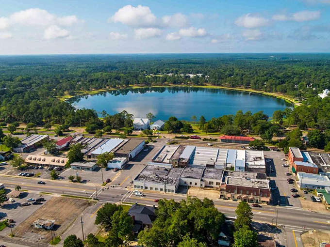 The perfect postcard moment: historic buildings surrounding Lake DeFuniak, where Victorian charm meets Florida sunshine in a scene straight out of a Hallmark movie.