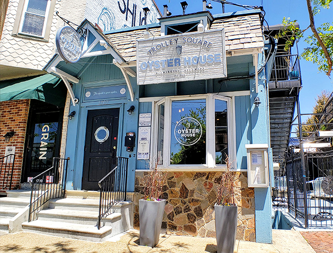 The blue facade of Trolley Square Oyster House beckons like a maritime mirage in urban Wilmington, promising seafood treasures behind that charming porthole door.
